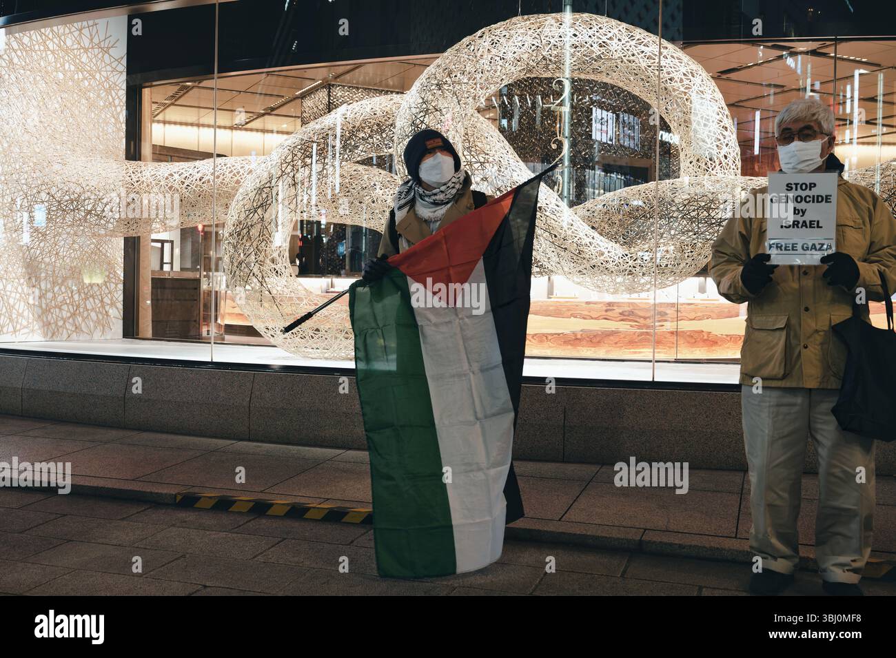 Activists display the Palestinian flag and a sign outside a modern ...