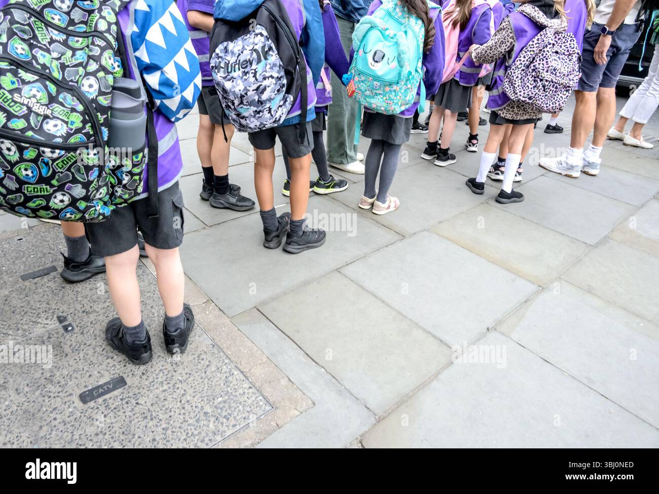 London, UK. Primary school children with brightly-coloured backpaks on ...