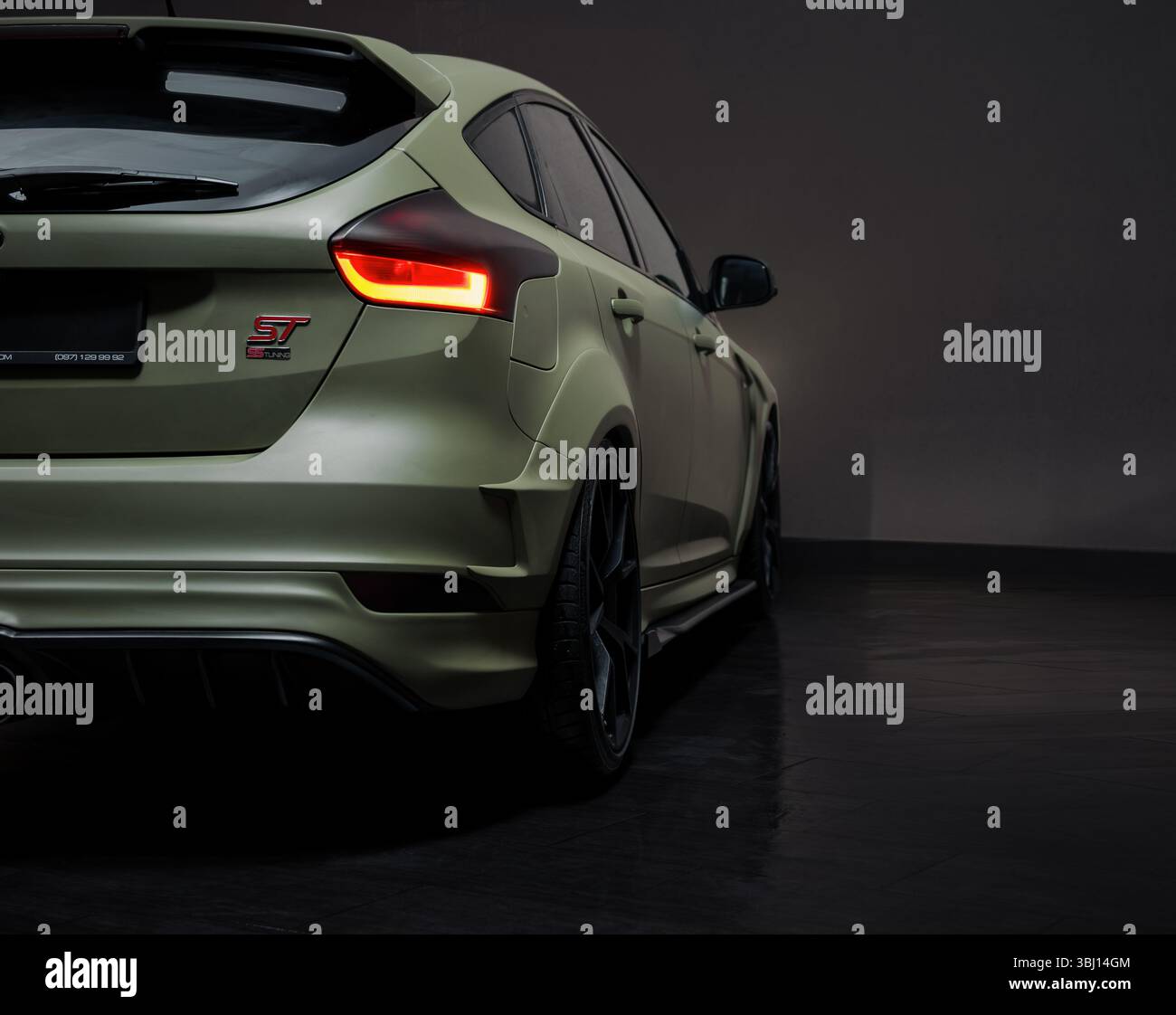 Olive Focus ST in dark garage. Rear right side view of satin green Ford ...