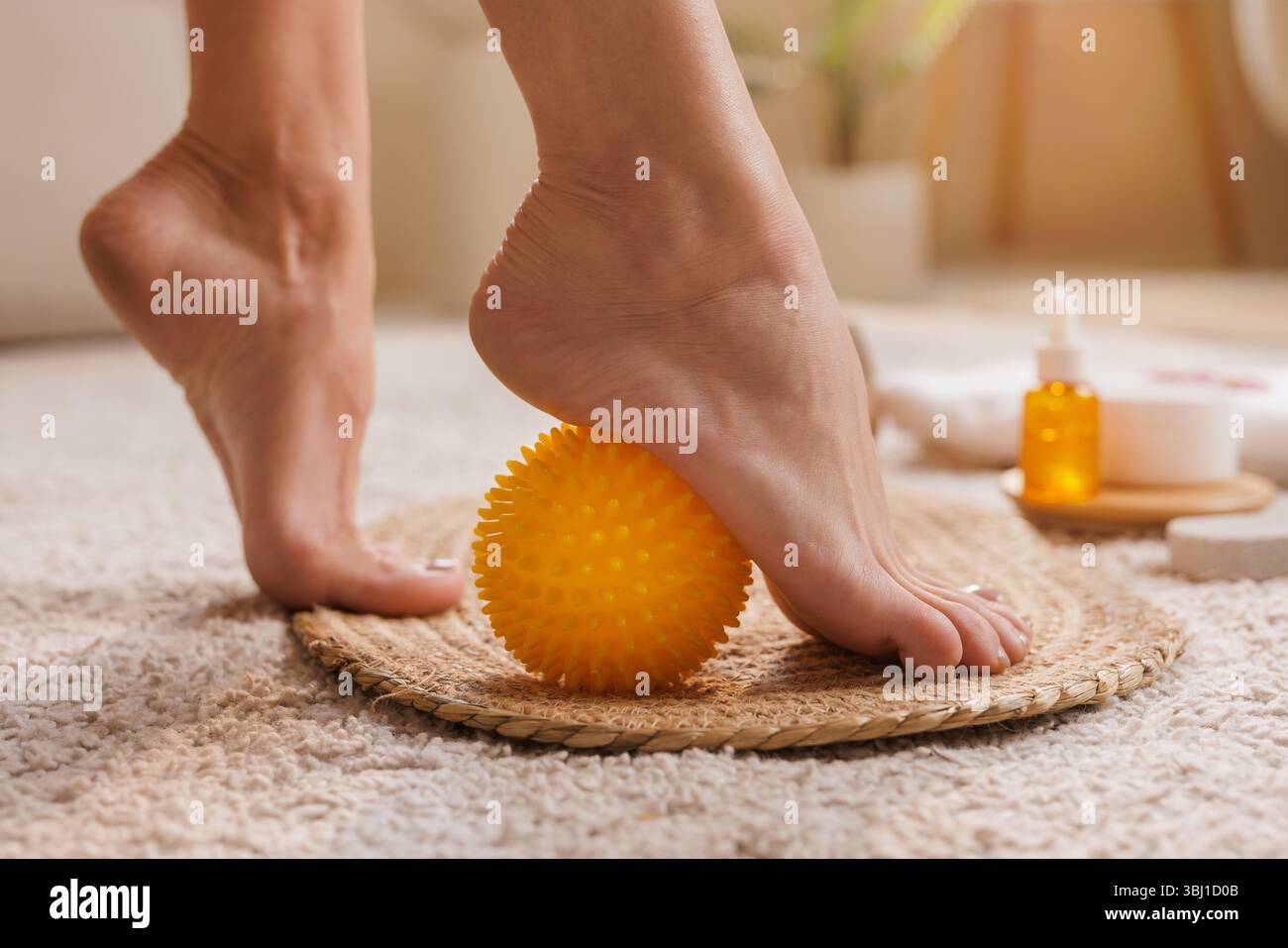 Foot massage with a spiky yellow ball on a cozy mat. Home spa scene ...