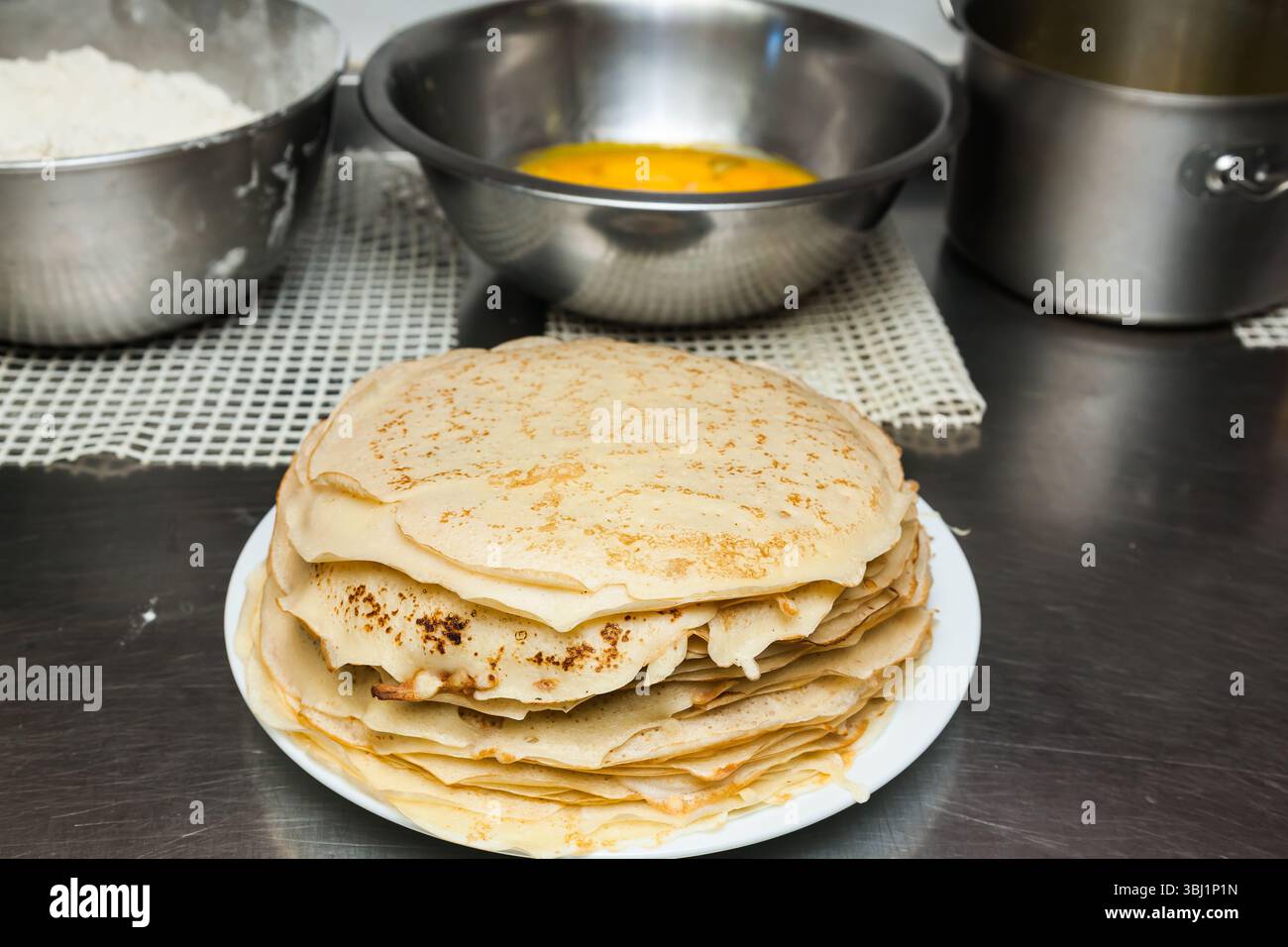 Ready-made pancakes are on the table, in a white plate, next to them ...