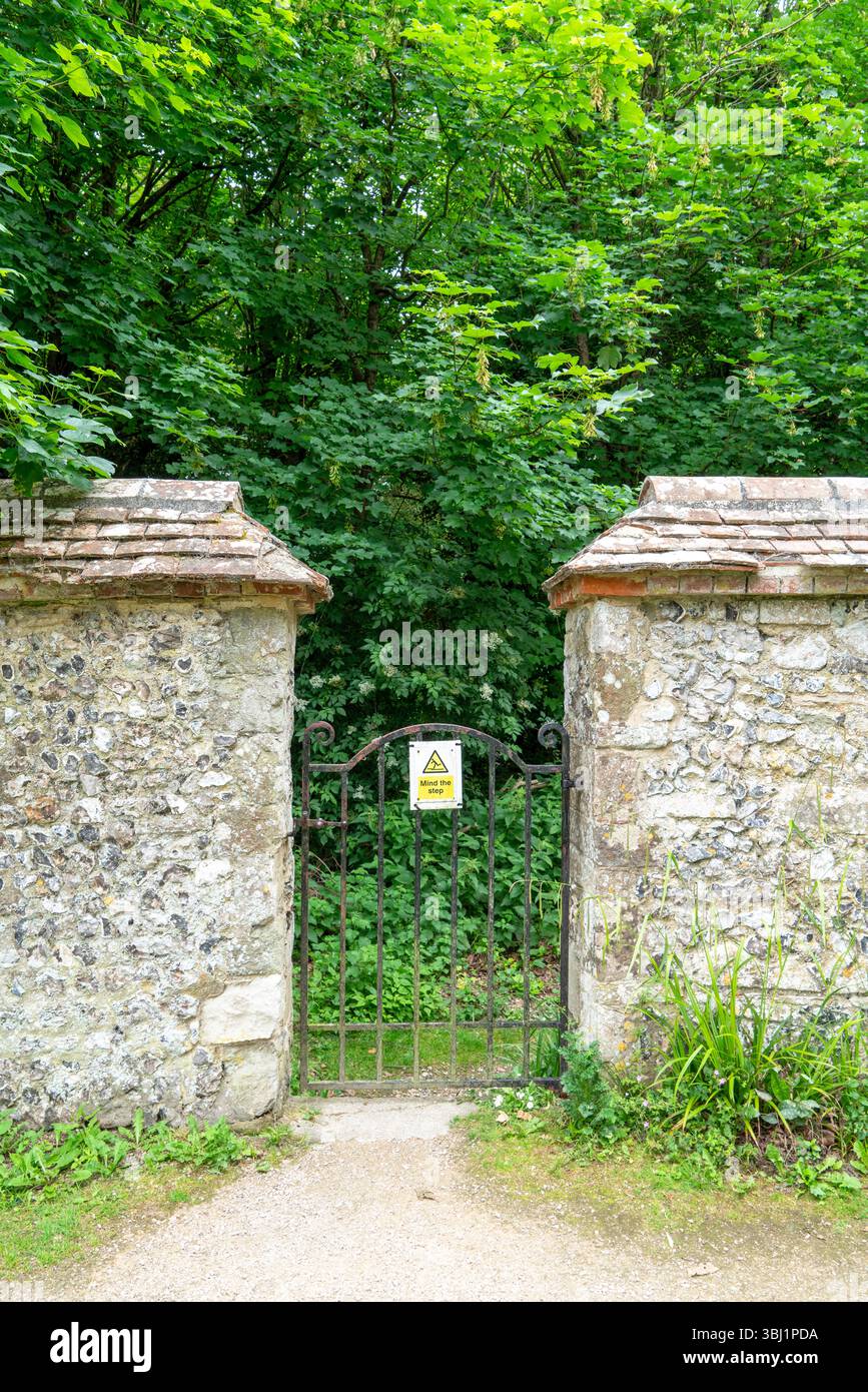 Metal gate with small hazard sign in stone wall Stock Photo - Alamy