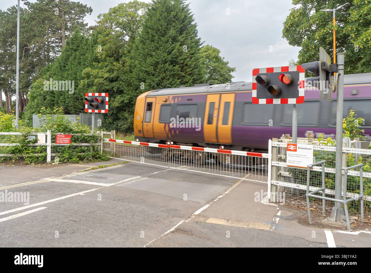 UK gated level crossing with barriers down & red lights flashing as a ...