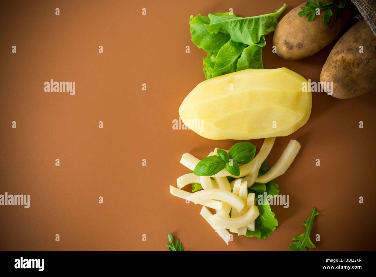 Potatoes in a sack and sliced into strips on a brown background Stock ...