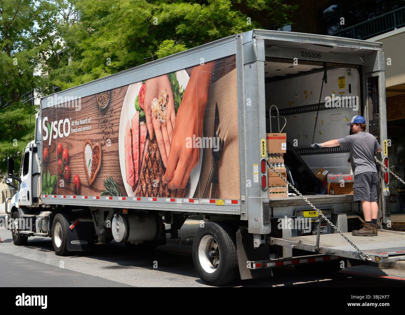 A Sysco wholesale food delivery truck and driver make a delivery to a ...