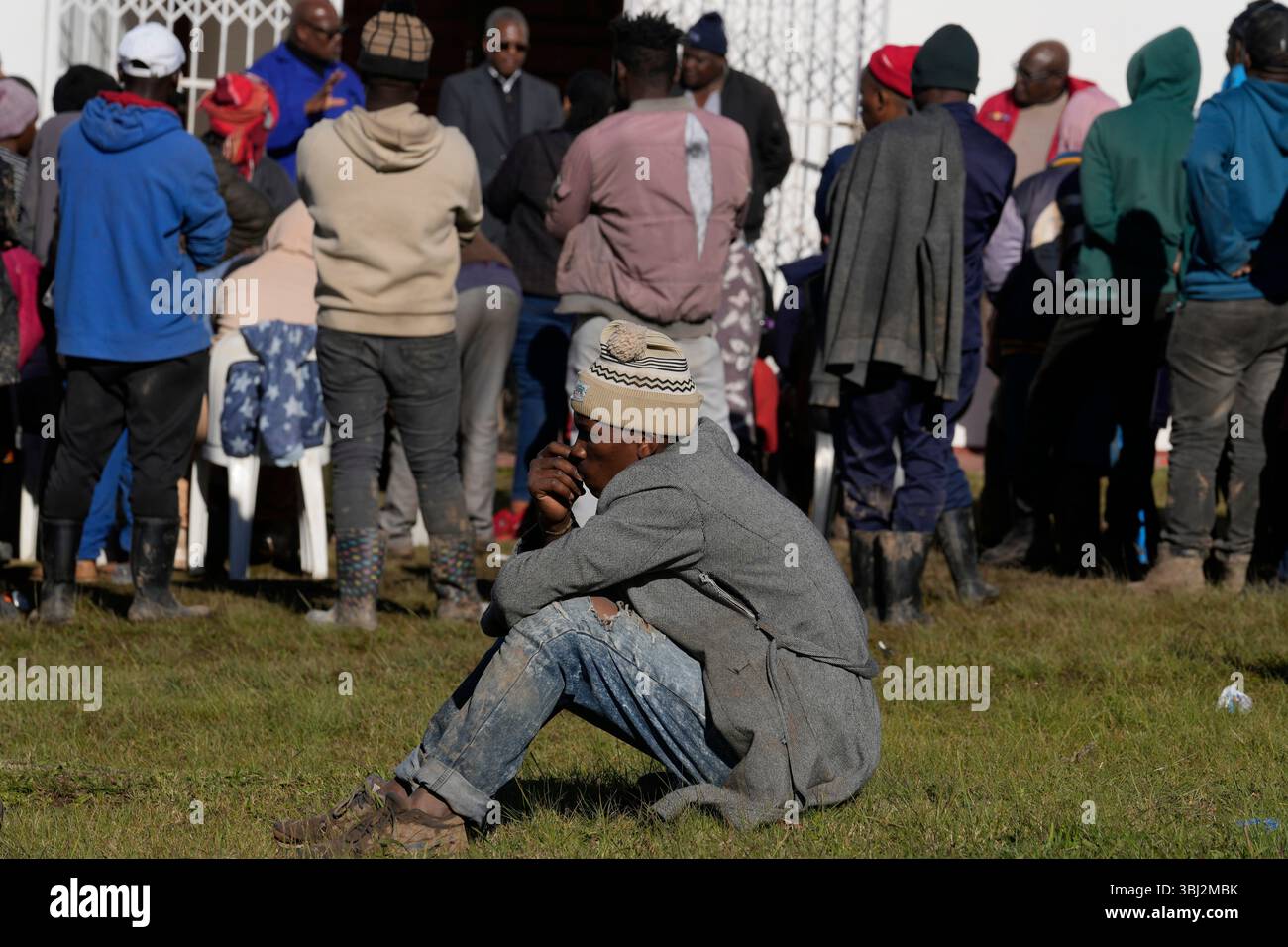A man sits on the ground as a minister addresses flood victims outside ...