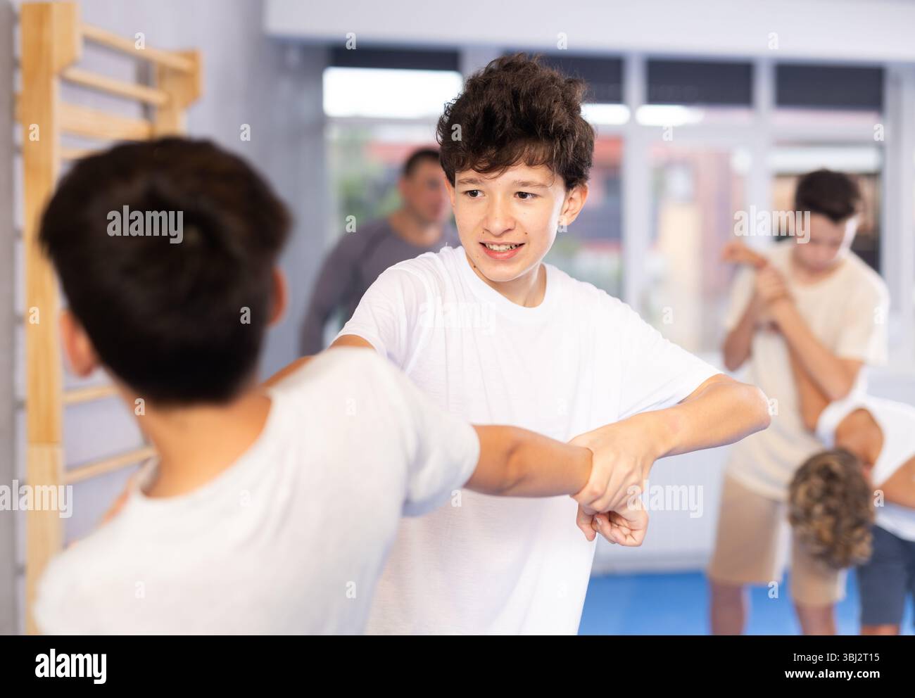 Diligent preteen student practicing self-defense techniques in pairs ...