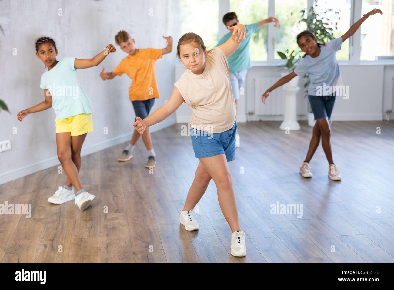 Energetic tween girl krumper dancing with group of children in studio ...