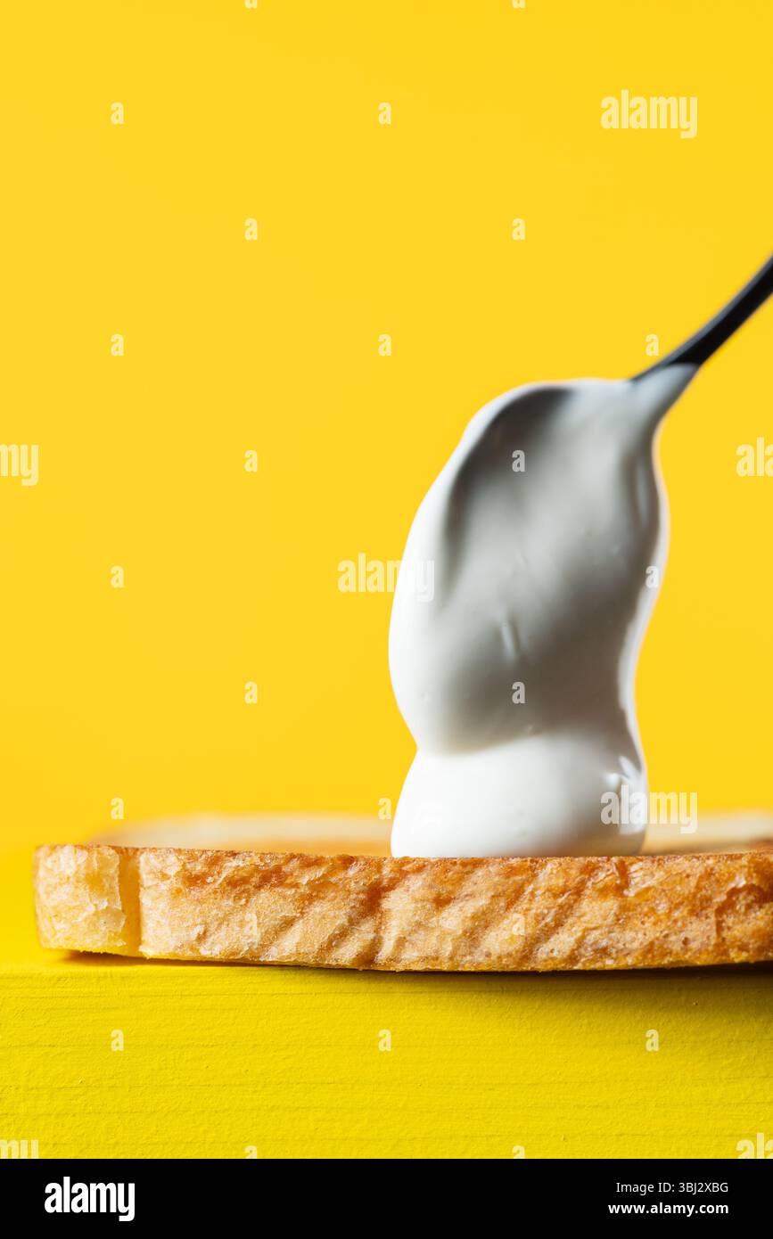 cook put mayonnaise on fresh toasted bread slice on yellow bright ...