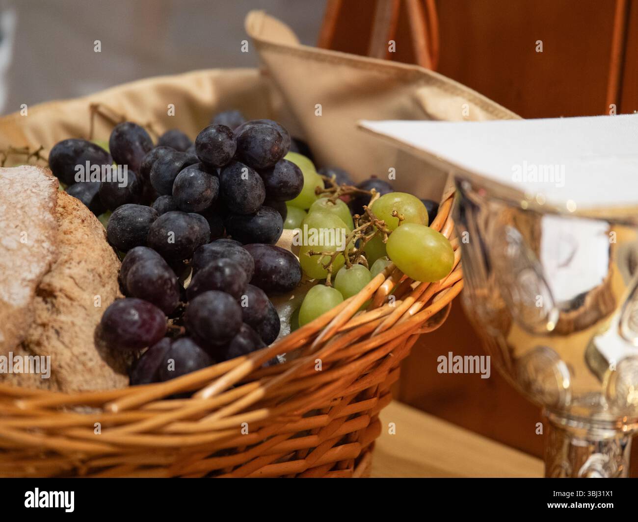 A close-up of a woven basket brimming with rustic bread and ripe grapes ...