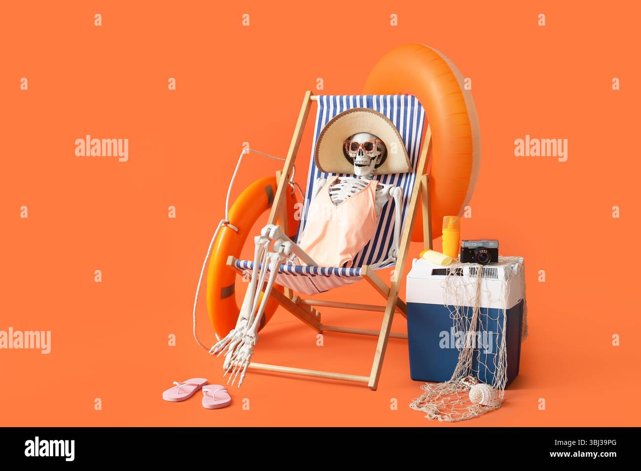 Human skeleton in deck chair with beach accessories on orange ...