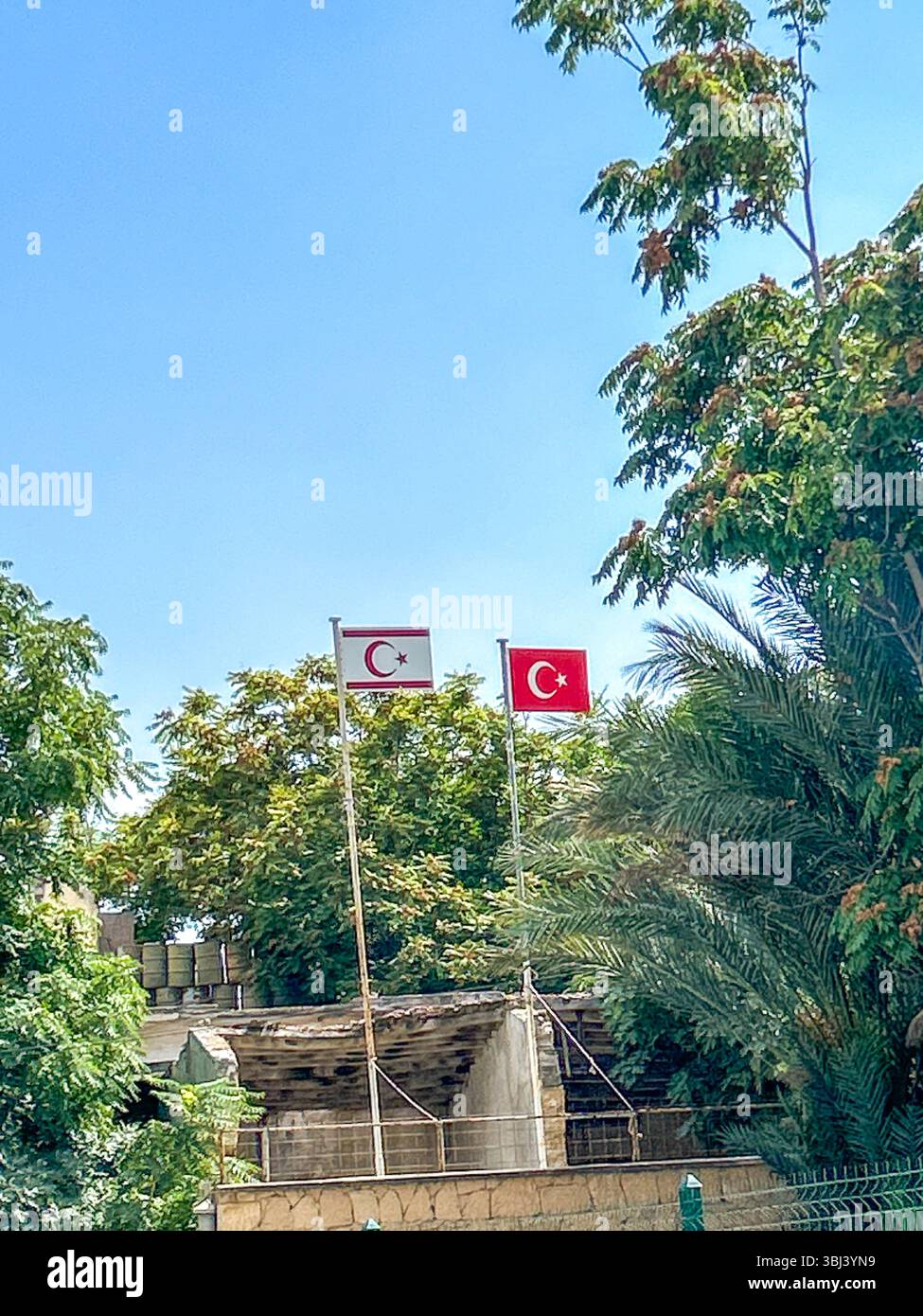 Two flags, of Northern Cyprus and Turkey, waving on tall poles above an ...