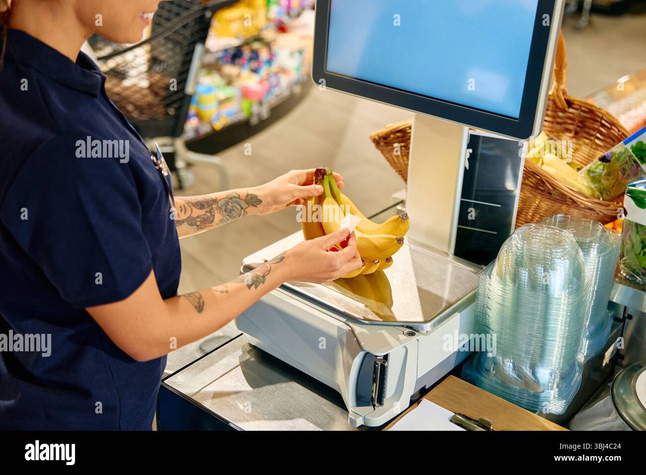 Supermarket employee in uniform weighing fresh bananas on a checkout ...