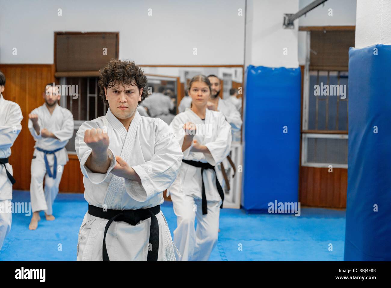 Group of karateka practicing fighting stances in a dojo, demonstrating ...