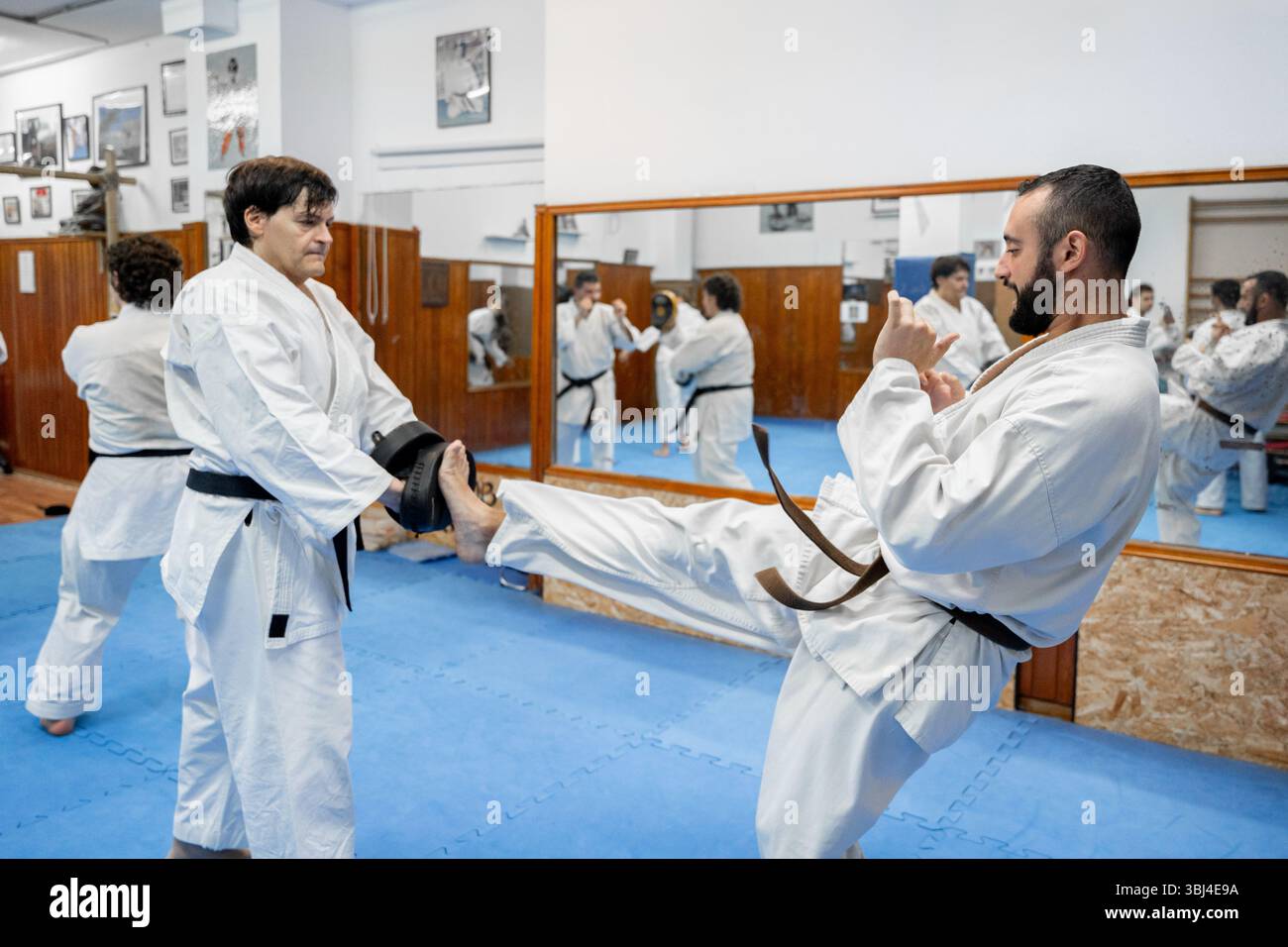 Karate athletes practicing kicking techniques during training in dojo ...