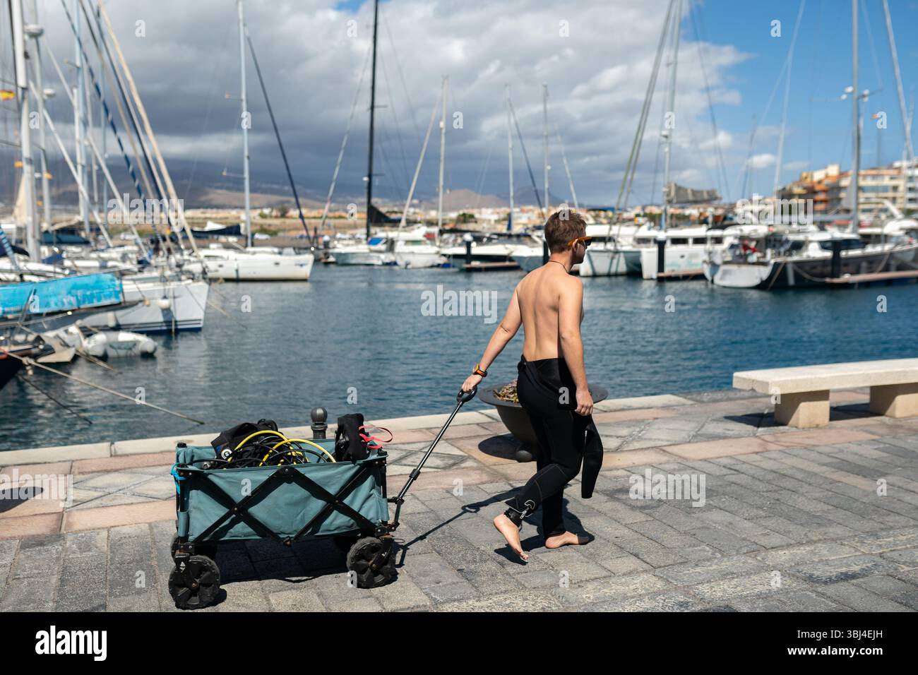 Diver pulling trolley with scuba diving equipment along the pier in a ...
