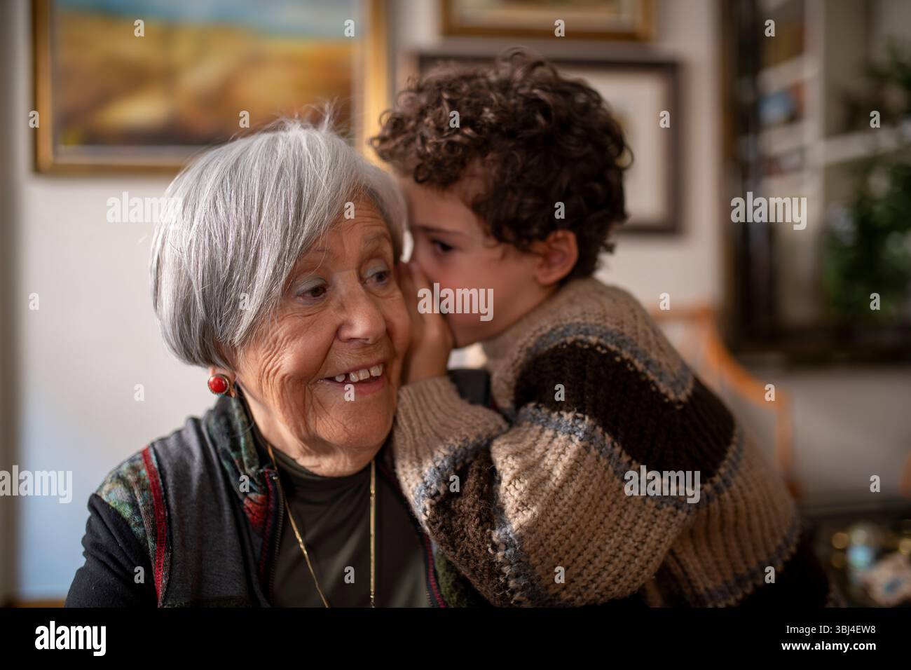 Happy grandchild whispering secrets to smiling grandmother, enjoying ...