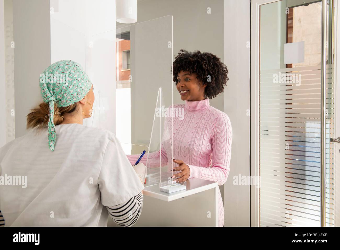 Patient and receptionist interacting at the reception desk of a dental ...