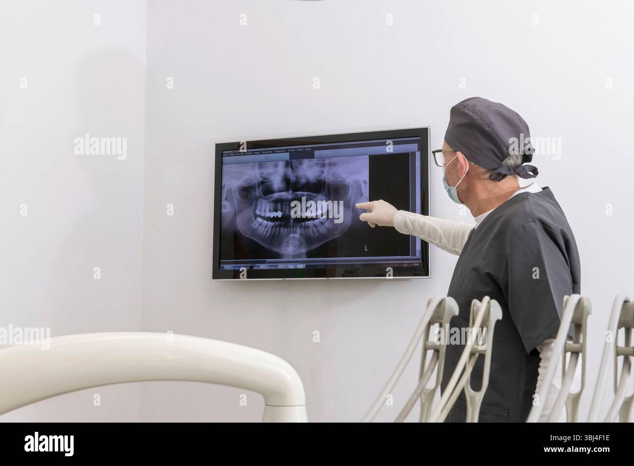 Dentist wearing surgical mask and uniform pointing at teeth x ray ...