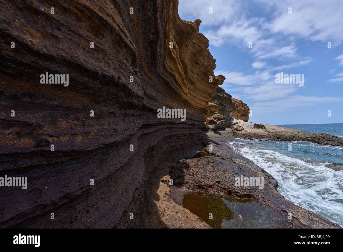 Stratified volcanic cliff above the ocean at Playa de Montaña Amarilla ...