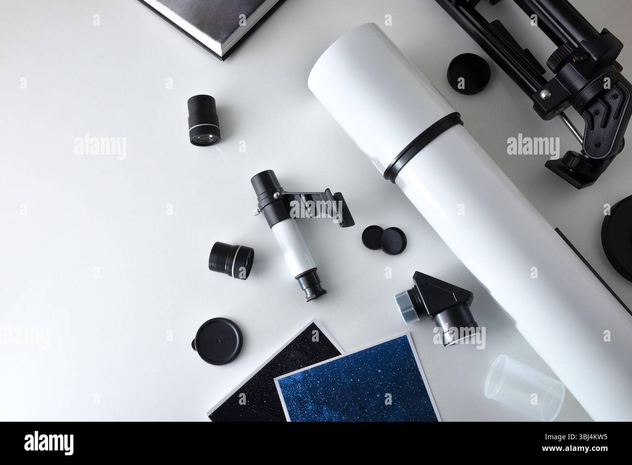 Parts and spares of a telescope on a white table with photos and a book ...