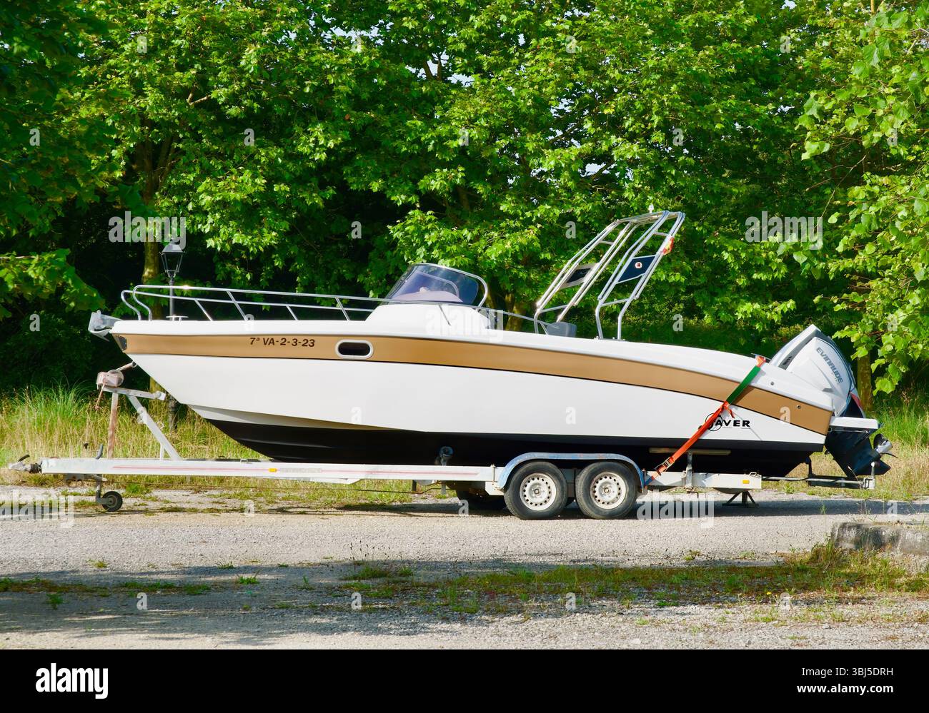 Powerboat with an outboard motor on a glide-path boat trailer parked at ...