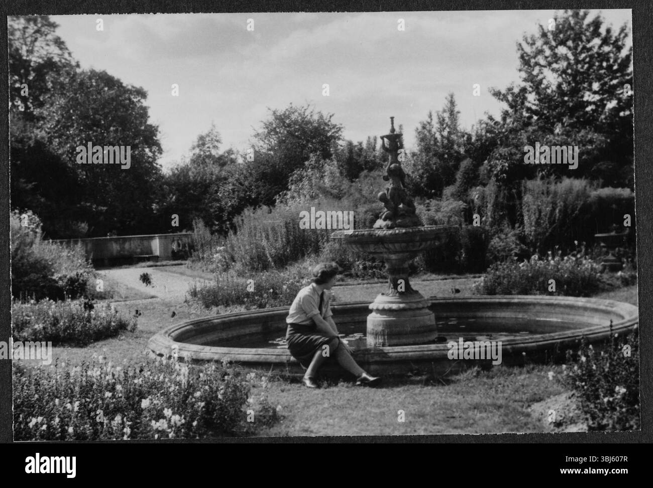 A woman in WAAF uniform, sitting on the edge of the pond in the formal ...