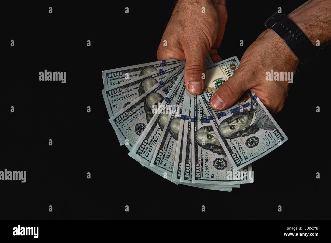 Two hands hold a fan of hundred dollar bills, showcasing the currency ...