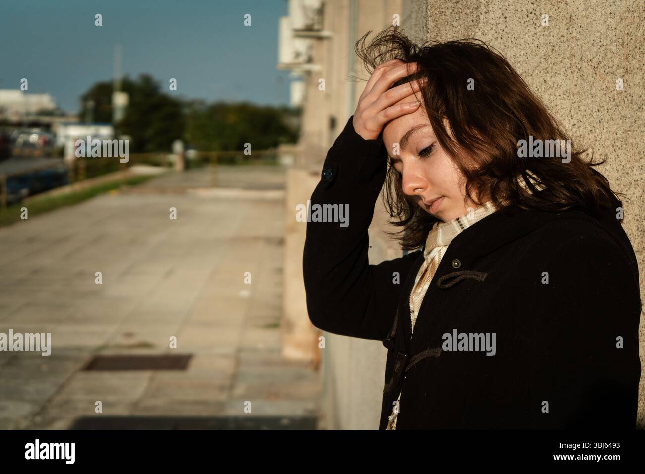 Young woman with a serious expression and relaxed posture leans her ...
