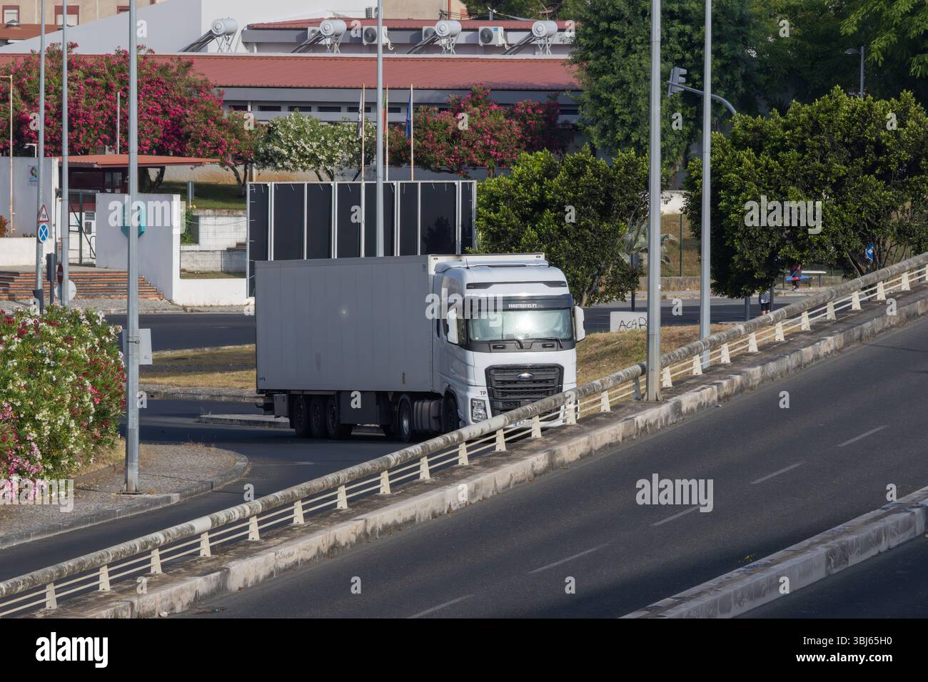 White articulated lorry transporting goods on an asphalt road near a ...