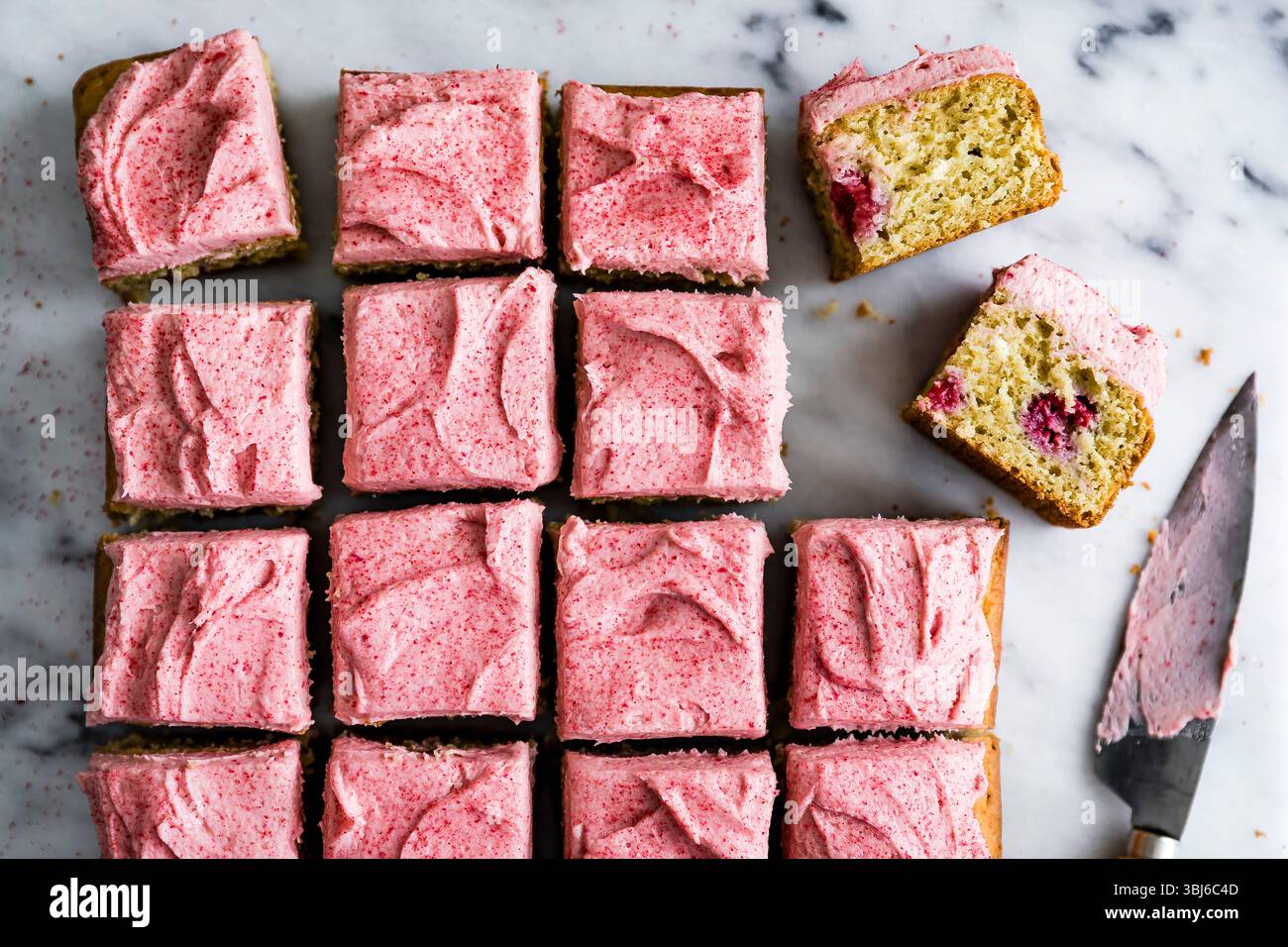 Top view of square cake pieces with pink frosting on a marble surface ...
