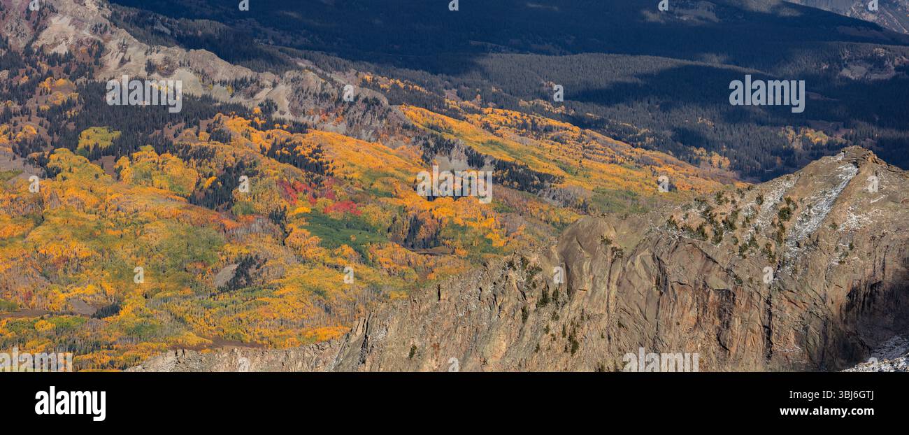 Rising above a sea of colorful autumn aspen trees is a jagged ridge of ...