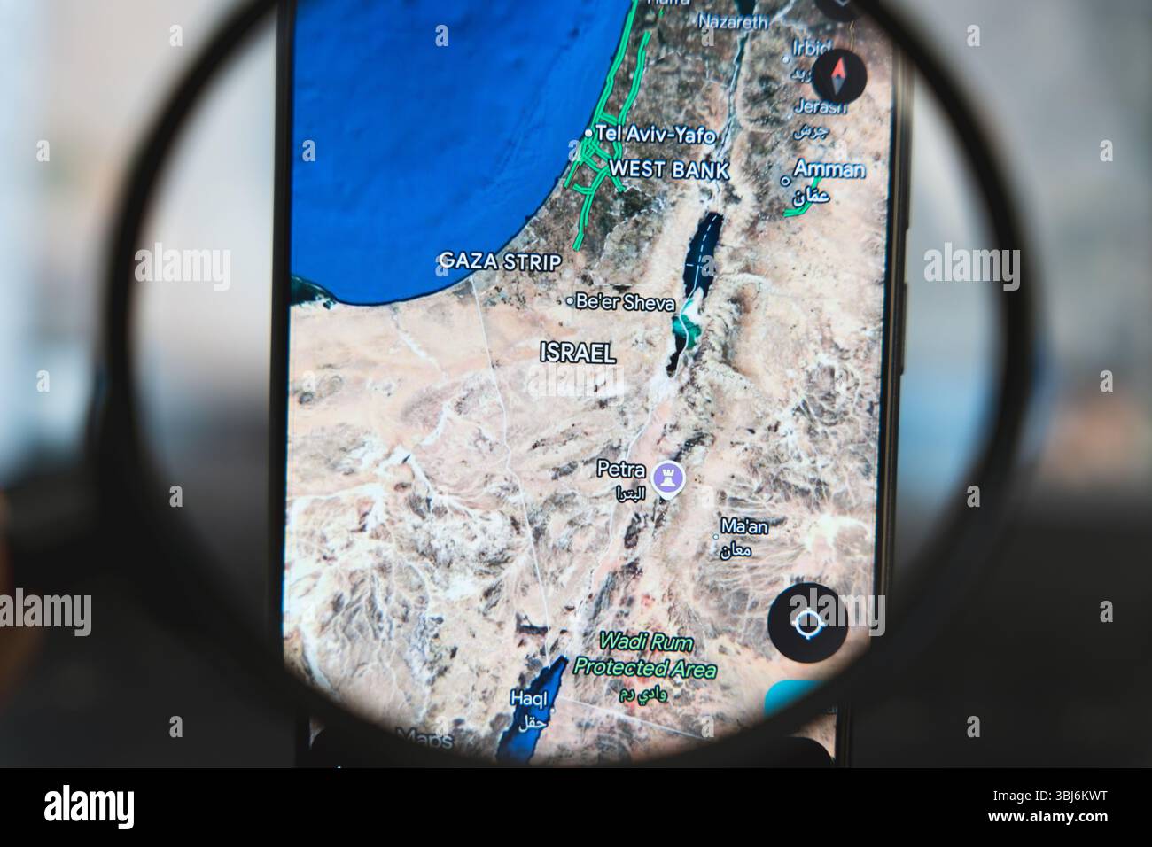 Magnifying glass over smartphone screen showing Israel country on ...