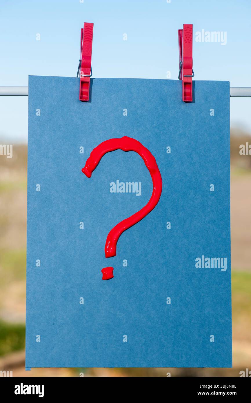 Red question mark painted with acrylic paint on blue cardboard with two ...