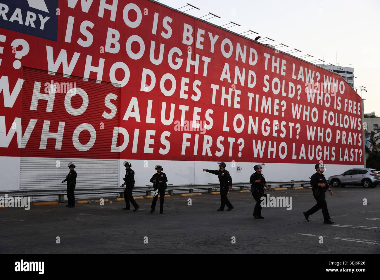 Los Angeles police officers form up beneath a mural by artist Barbara ...