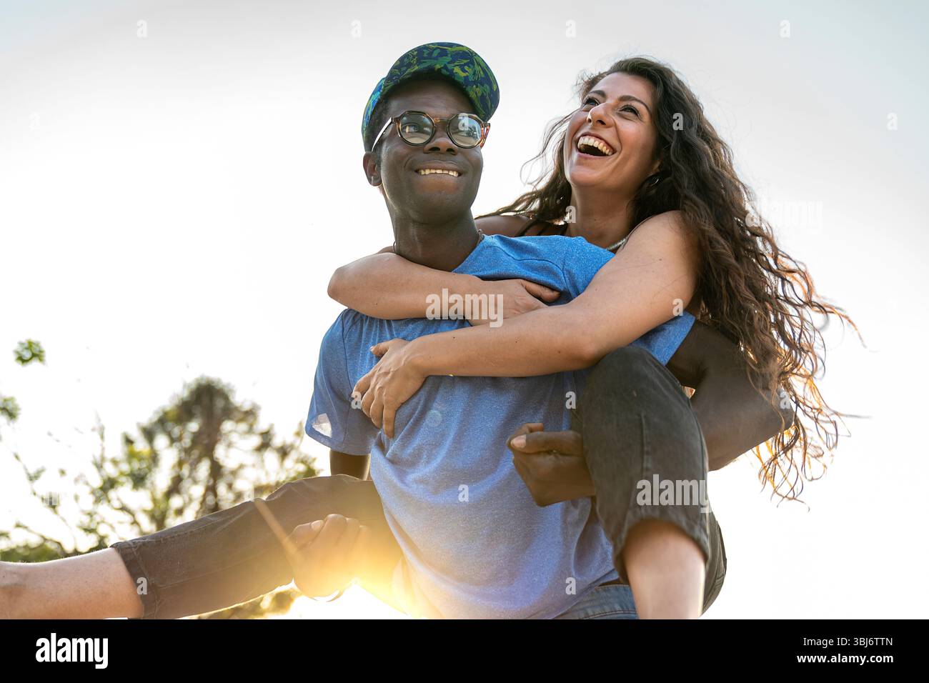A joyful young diverse couple laughs while the man gives his partner a ...