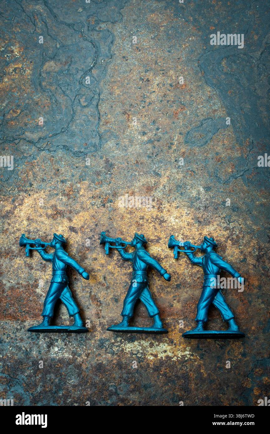 Three small blue toy soldiers are positioned on a rough, textured ...