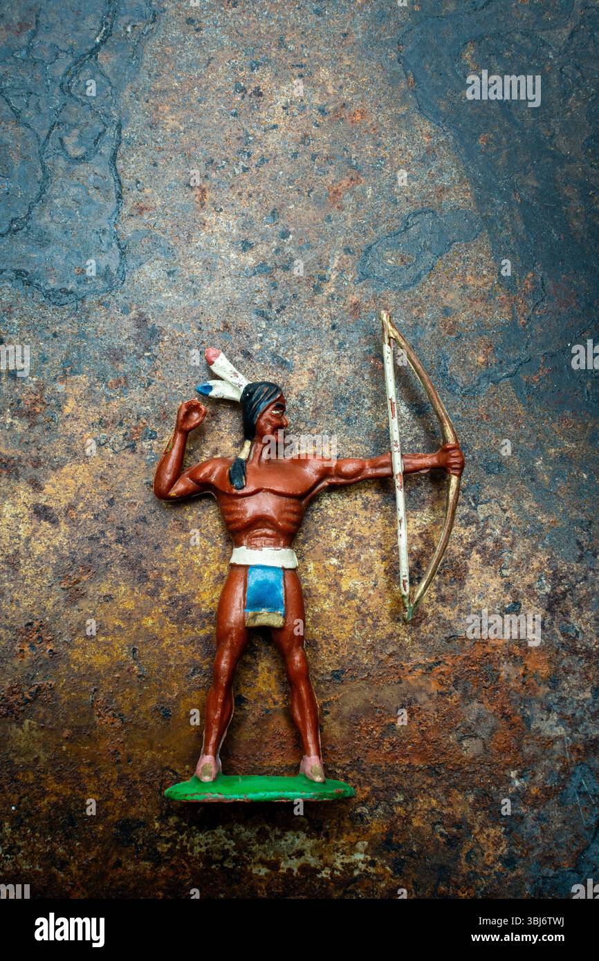 A bright plastic toy archer stands poised with his bow drawn back ...