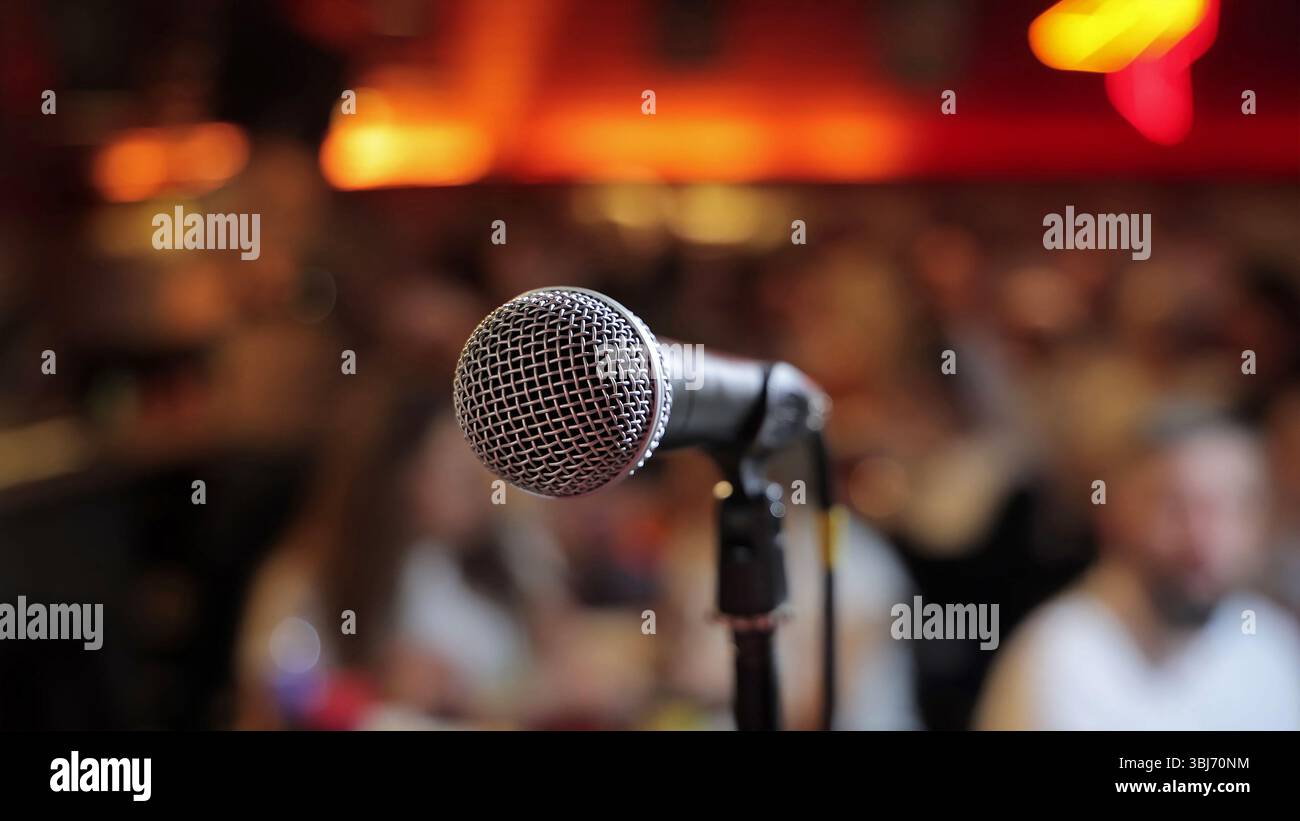 Microphone on stage with blurred audience in background. A close-up of ...