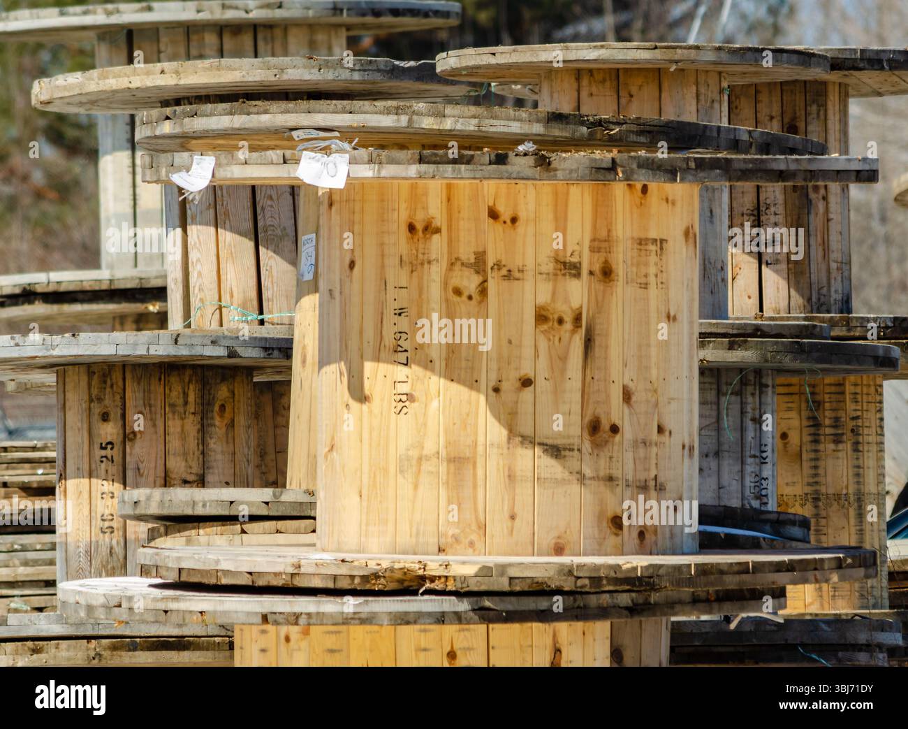 Stacks of empty wooden cable spools outside in the sun Stock Photo - Alamy
