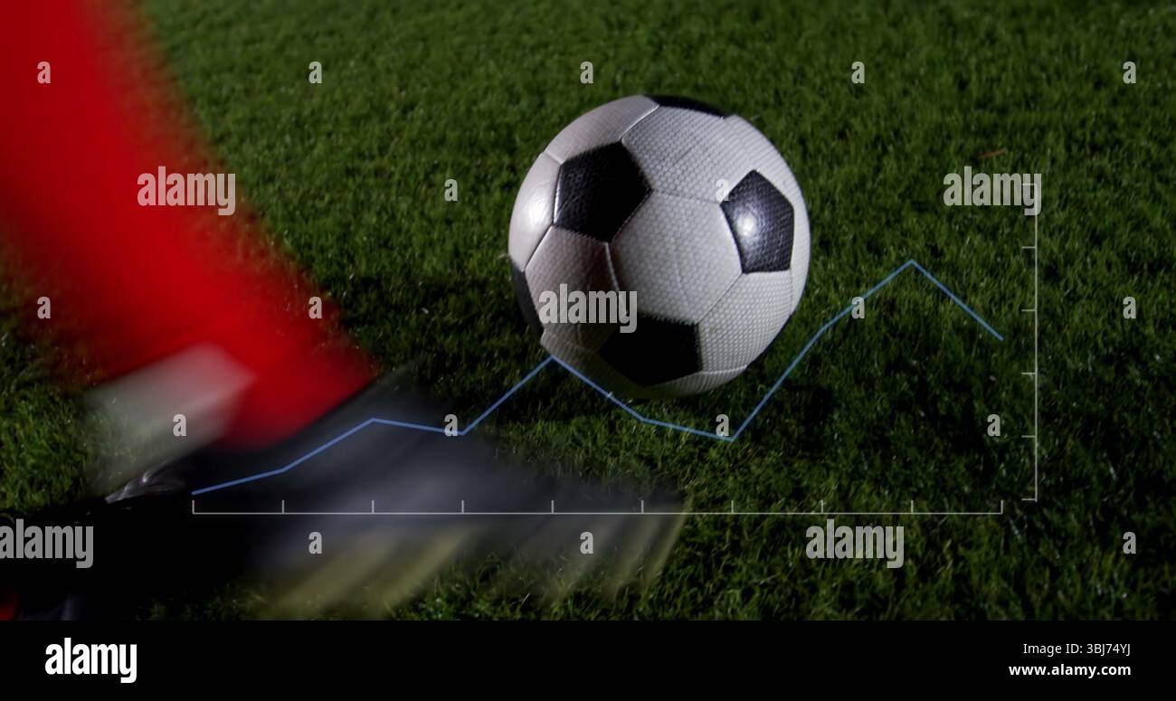 Swinging leg wearing red sock sending soccer ball rolling on floodlit ...