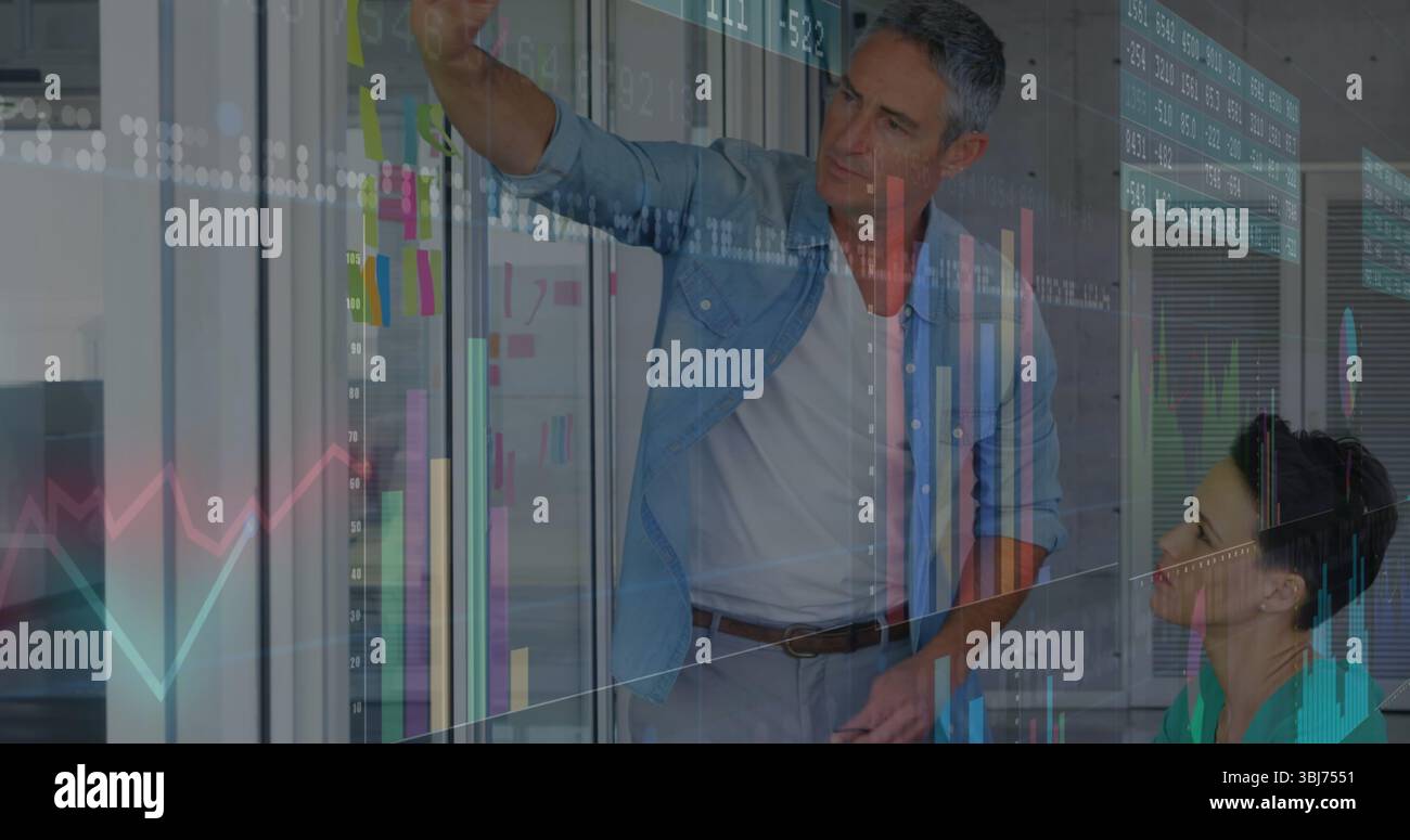 Collaborating colleagues marking sticky notes on glass partition in ...