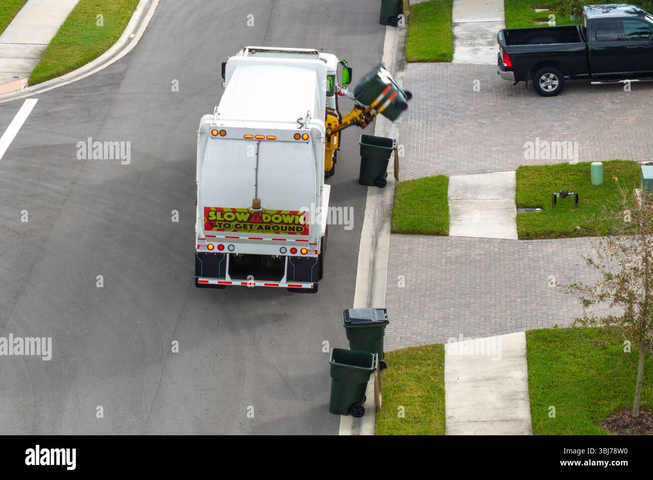 Automated modern garbage collector truck loading waste on Florida town street. Municipal ...