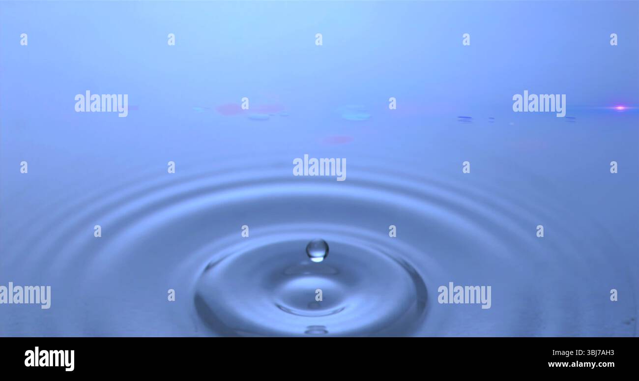 Capturing clear water droplet forming ripples on blue surface in macro ...