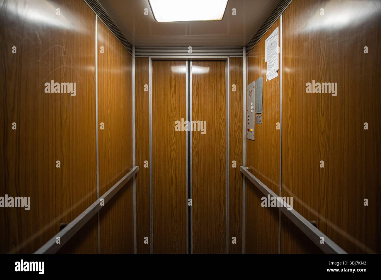 Interior inside a closed clean old Soviet elevator car lined with wood ...