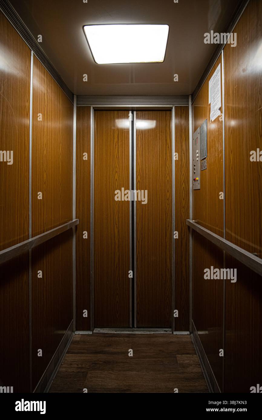 Interior inside a closed clean old Soviet elevator car lined with wood ...