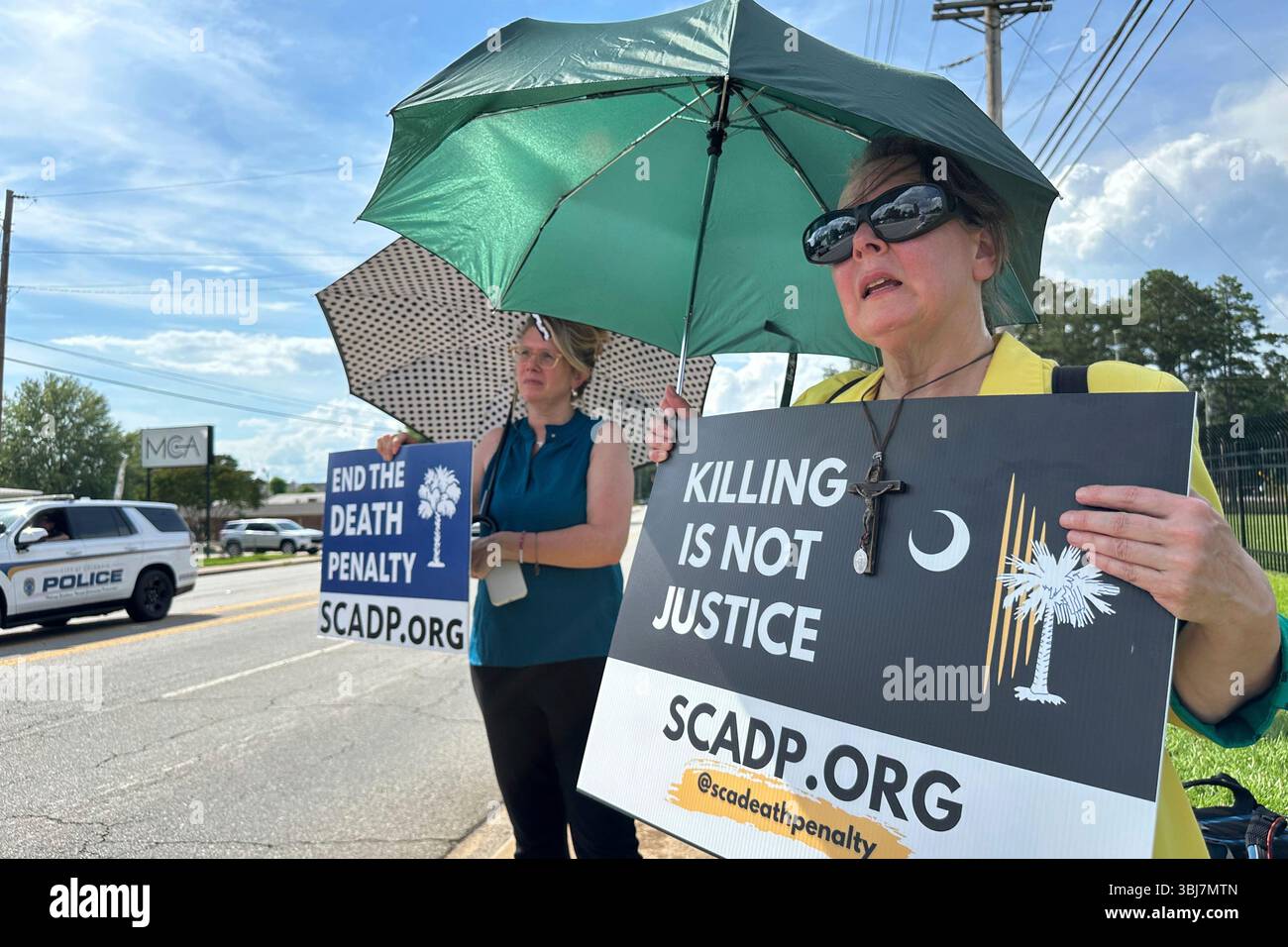Protesters shielding themselves in the 84-degree heat await the planned ...