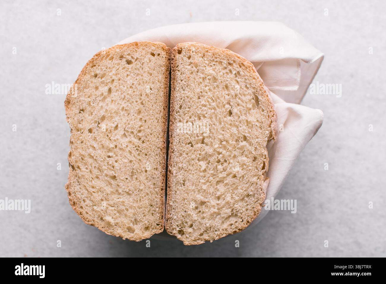 Overhead view of sliced homemade artisan bread on marble countertop, top view of cross-section ...