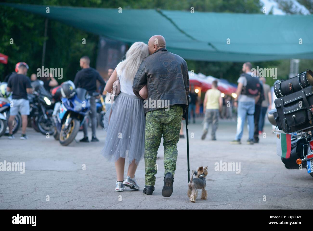 A couple walks closely together with their small dog during the Moto ...