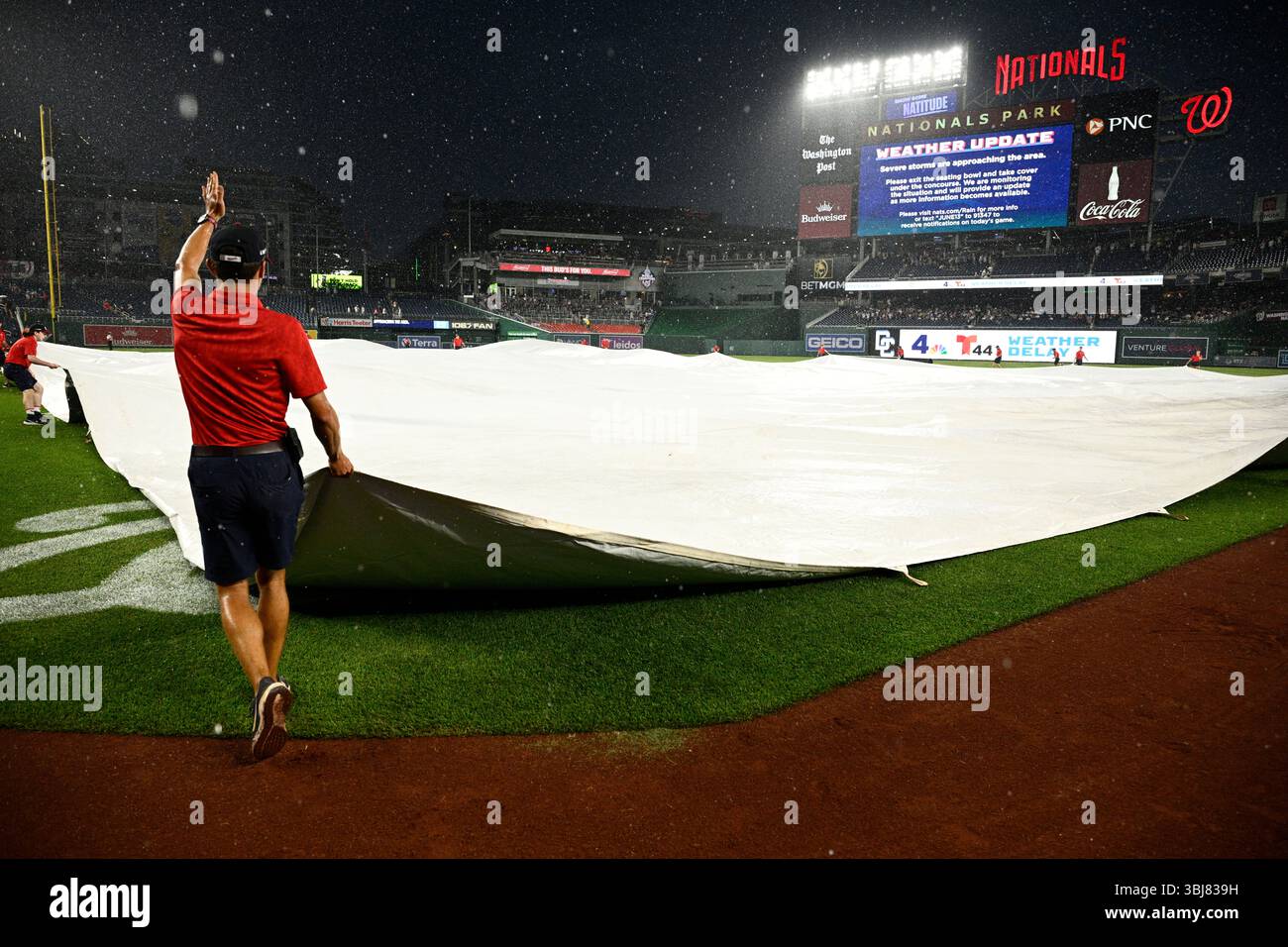 The Washington Nationals grounds crew spreads the tarp on the field ...
